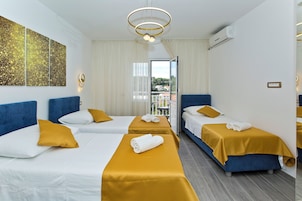 Quarto de hotel com duas camas, uma janela grande e vista para a cidade.