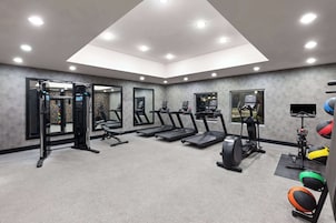 Uma academia com esteiras, máquina de musculação e bolas de exercício.