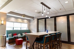 Um interior moderno com uma ilha grande, banquetas de bar, um sofá com almofadas estampadas e uma janela com vista.