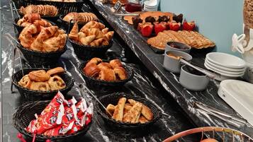 Buffet com diversas opções de comida, incluindo doces, frutas e acompanhamentos.