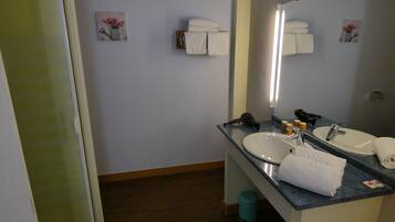 Casa de banho com lavatório, espelho e porta-toalhas.