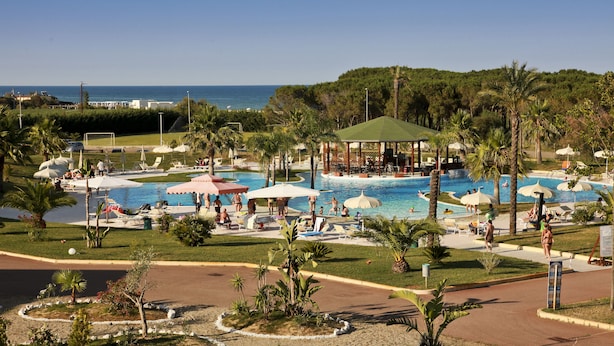 Resort com grande área de piscina, espreguiçadeiras e um gazebo.