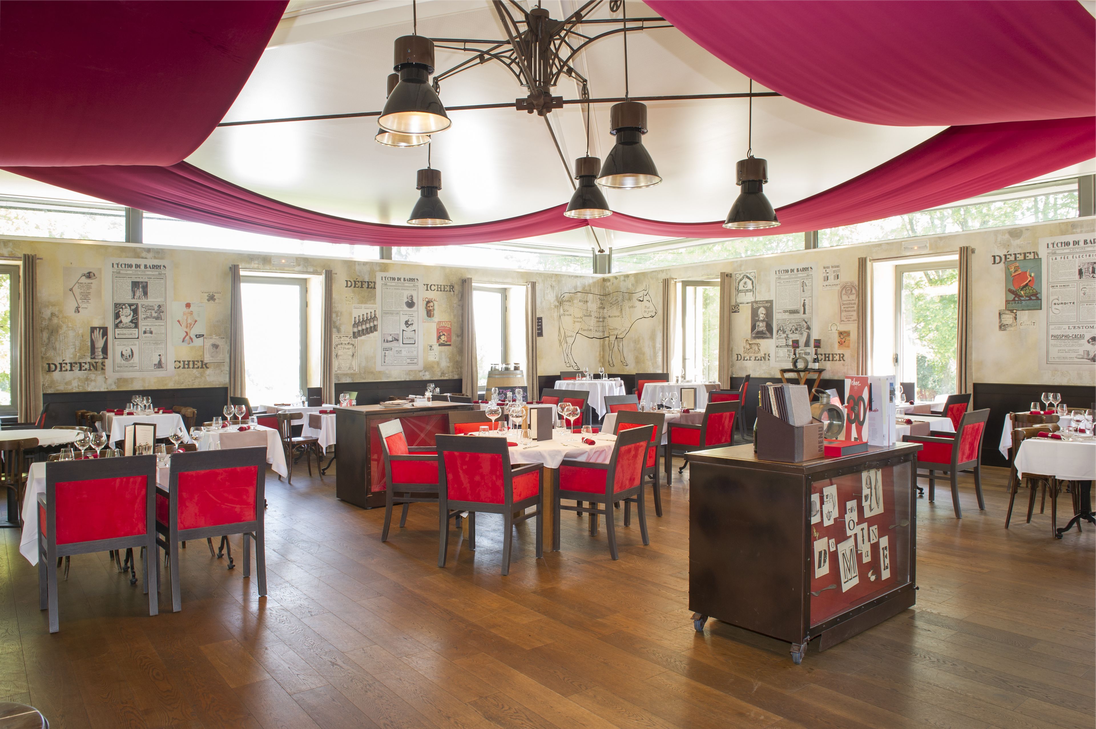 Restaurante com piso de madeira, cadeiras vermelhas e mesas preparadas para refeições.
