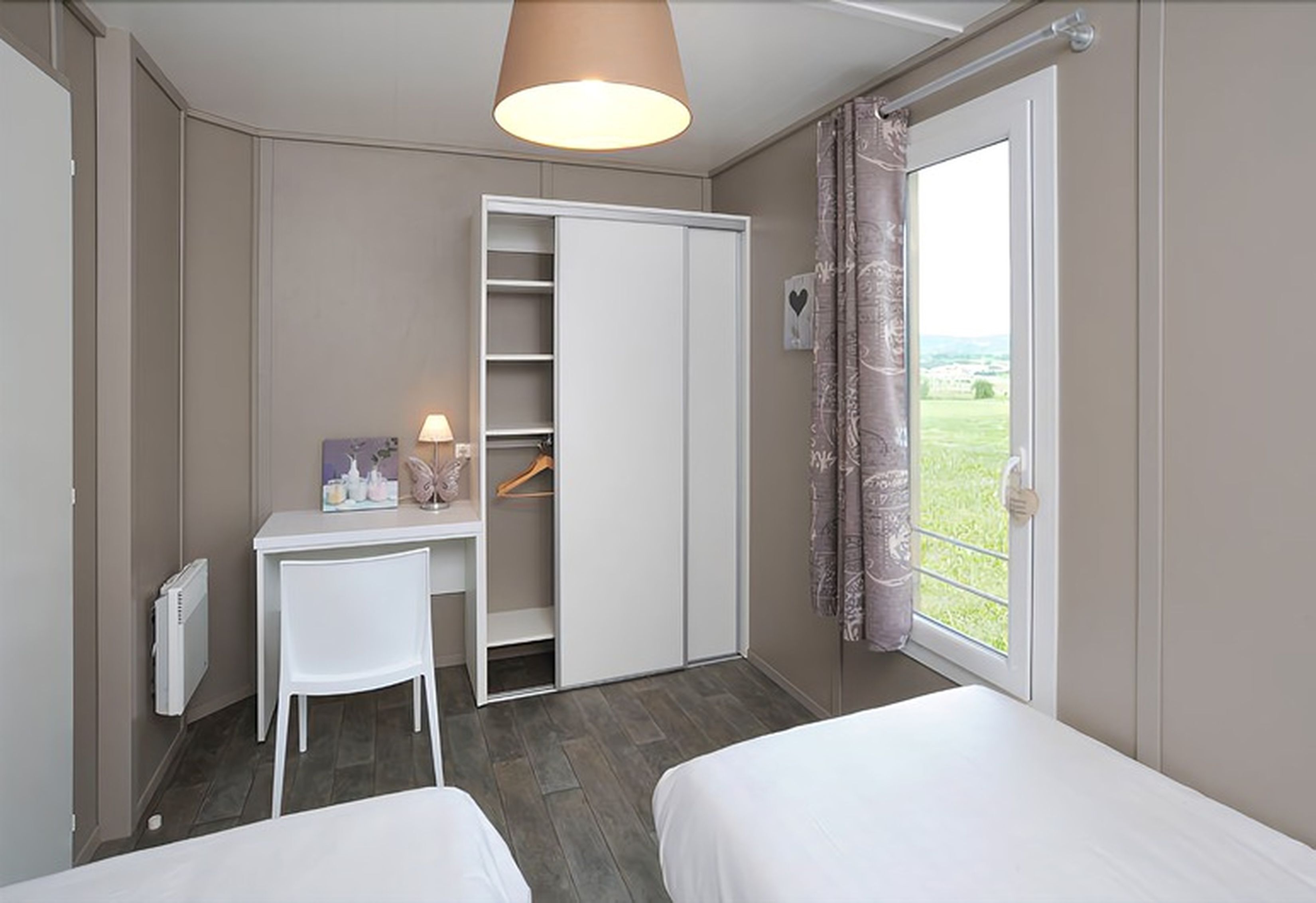 Um quarto com cama, escrivaninha, cadeira, guarda-roupa e janela com cortinas.