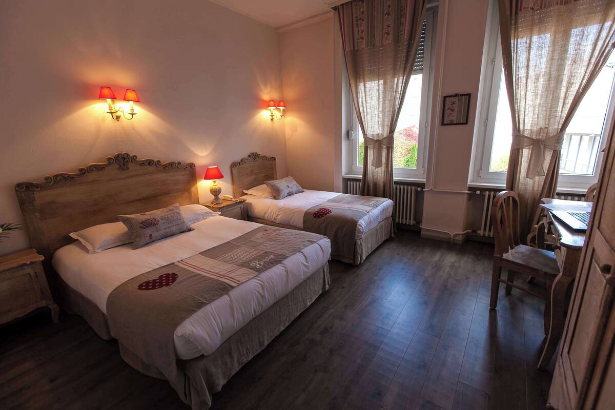 Quarto de hotel com duas camas, uma escrivaninha e uma cadeira.