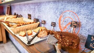 Vitrine de pastelaria com diversos produtos de panificação e um aviso sobre bolo de chocolate.