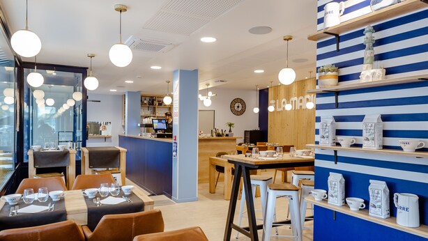 Um restaurante moderno com esquema de cores azul e branco, mobiliário de madeira e diversas opções de assento, incluindo mesas e cadeiras.