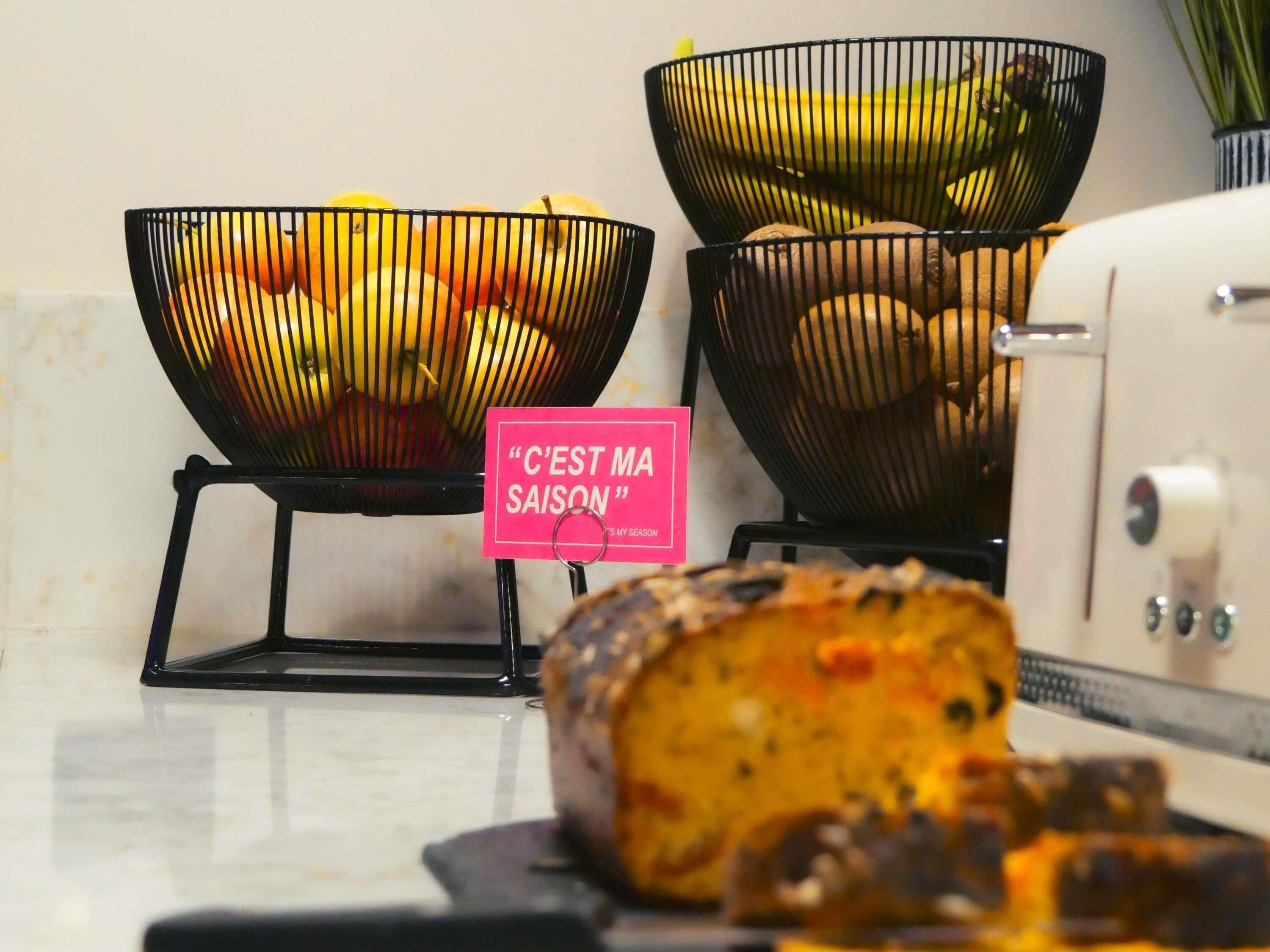 Uma bancada de cozinha com duas cestas de fruta e uma gaveta de pão.