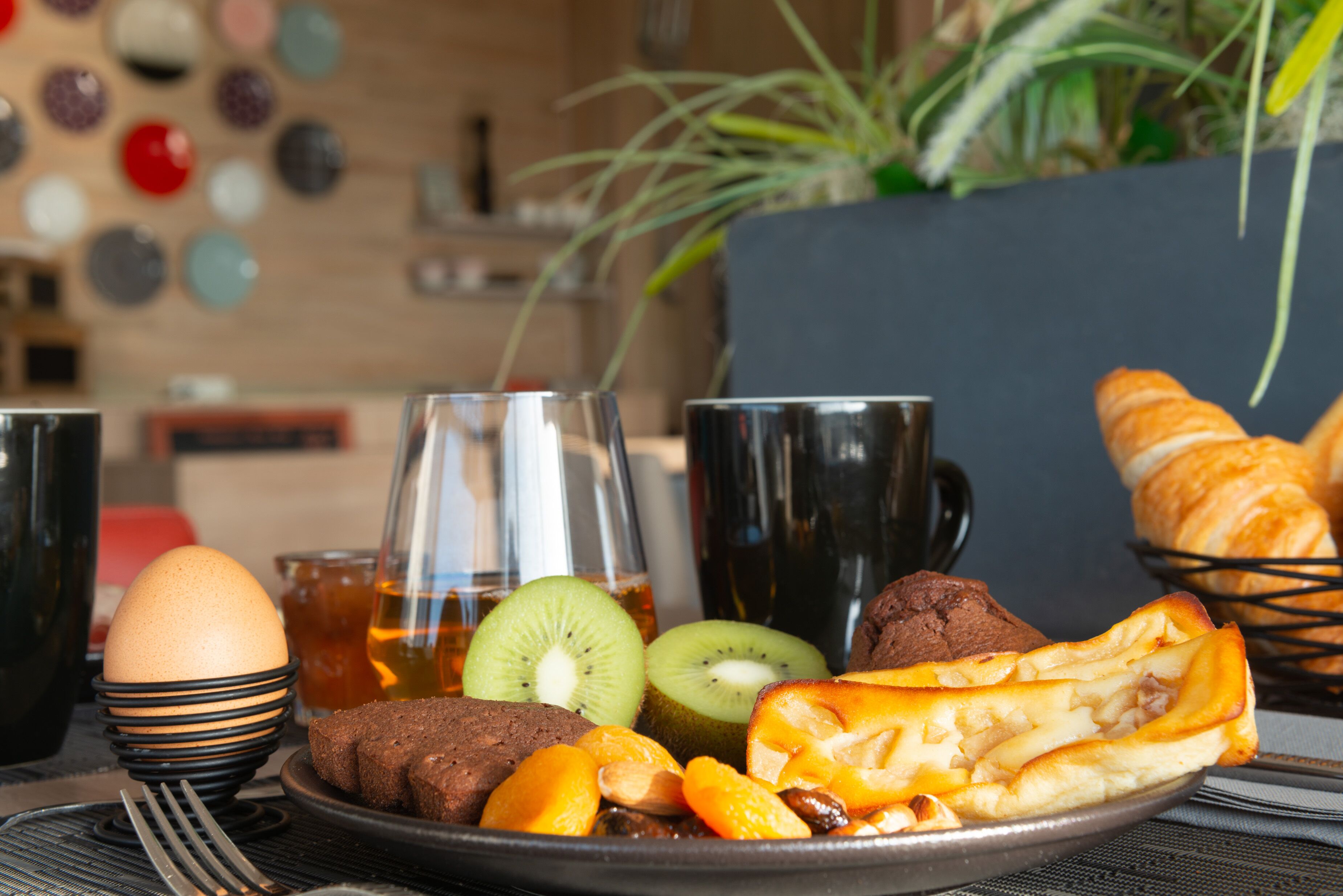 Prato de café da manhã com ovos, kiwi, fatias de laranja e doces.