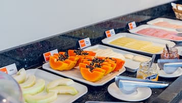 Buffet com diversas frutas e queijos, incluindo mamão e melão.