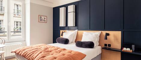 Um quarto moderno com uma cama grande, cabeceira escura e uma mesinha de cabeceira.