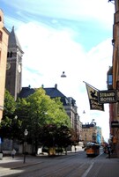 Rua com elétrico, torre do relógio e placa do Strand Hotel.