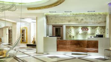 Uma área de recepção com um balcão de mármore, um painel de parede em madeira e um candelabro.