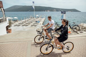Uma área costeira com calçada pavimentada, bicicletas e guarda-sóis de praia.