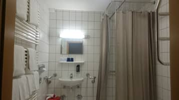 Casa de banho com lavatório branco, espelho, cortina de chuveiro e barra para toalhas.