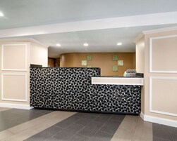 Uma área de recepção com balcão de check-in, parede estampada e chão em azulejos.