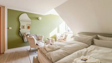 Quarto com cama, duas cadeiras, espelho e parede verde.