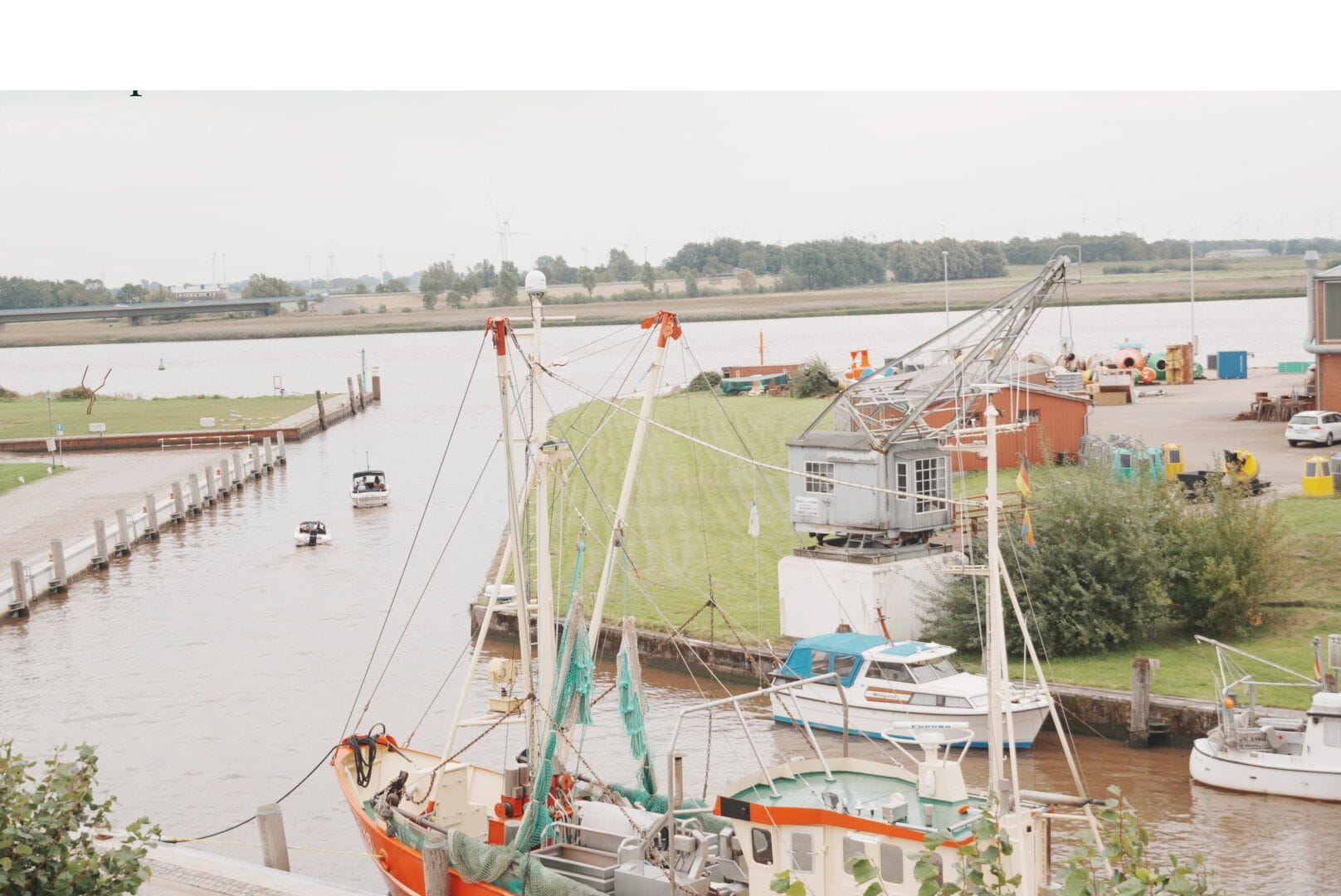 Uma marina com barcos atracados, área gramada e um edifício ao fundo.