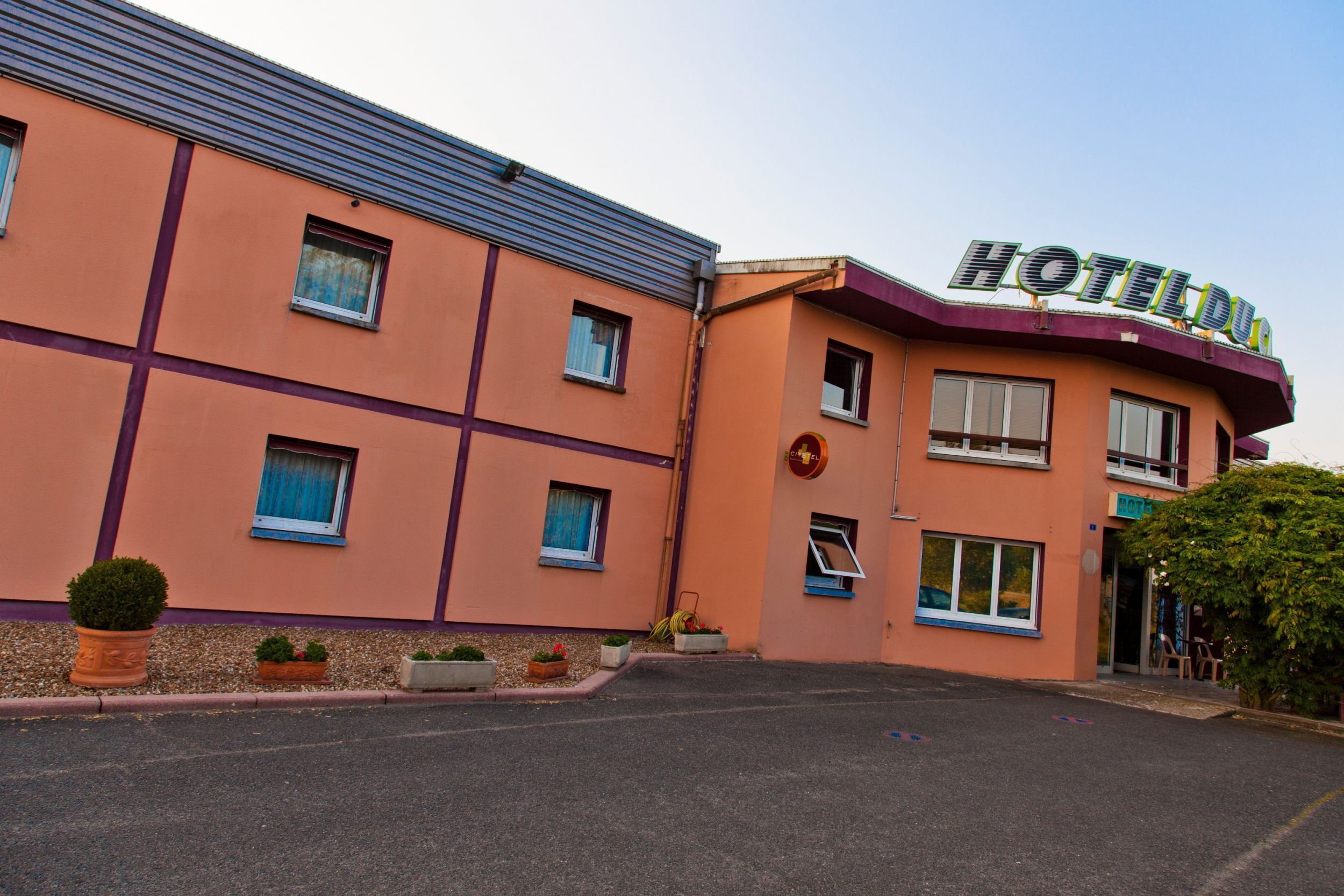 Um hotel com fachada cor de pêssego, várias janelas e uma placa com a palavra 'HOTEL'.