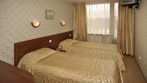 Quarto de hotel com duas camas, televisão e janela com cortinas.