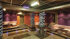 Uma área de estar moderna com um pilar listrado em preto e branco, um sofá e um bar com banquetas.