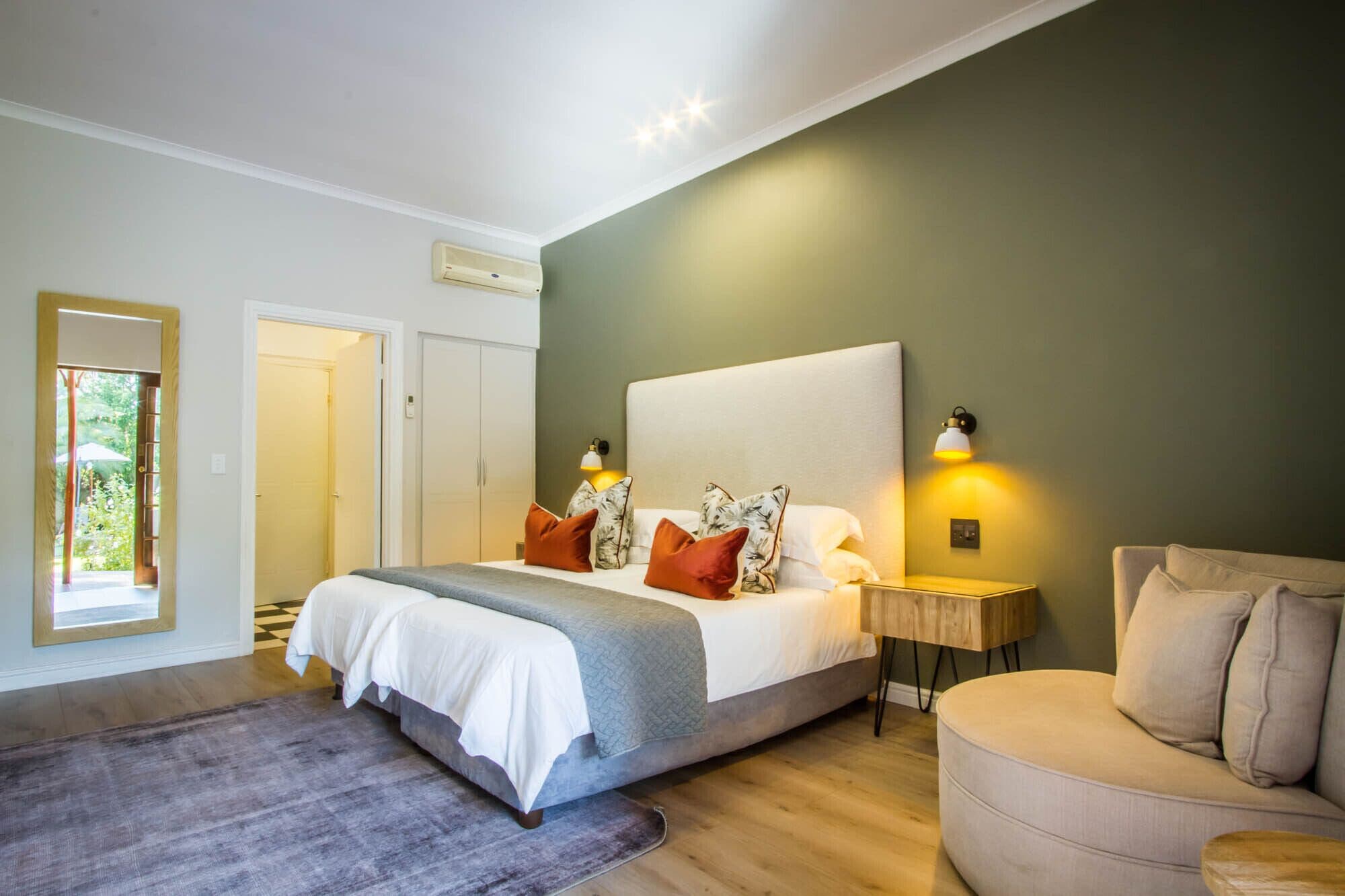 Quarto com cama, mesa de cabeceira, abajur e sofá.