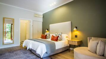 Quarto com cama, mesa de cabeceira, abajur e sofá.