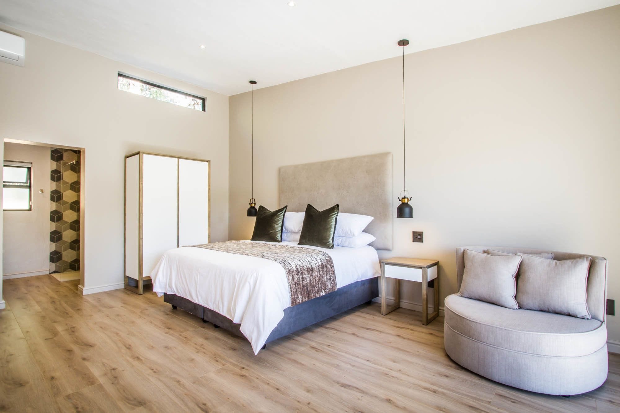 Quarto moderno com uma cama grande, mesas de cabeceira, um sofá e um guarda-roupa.