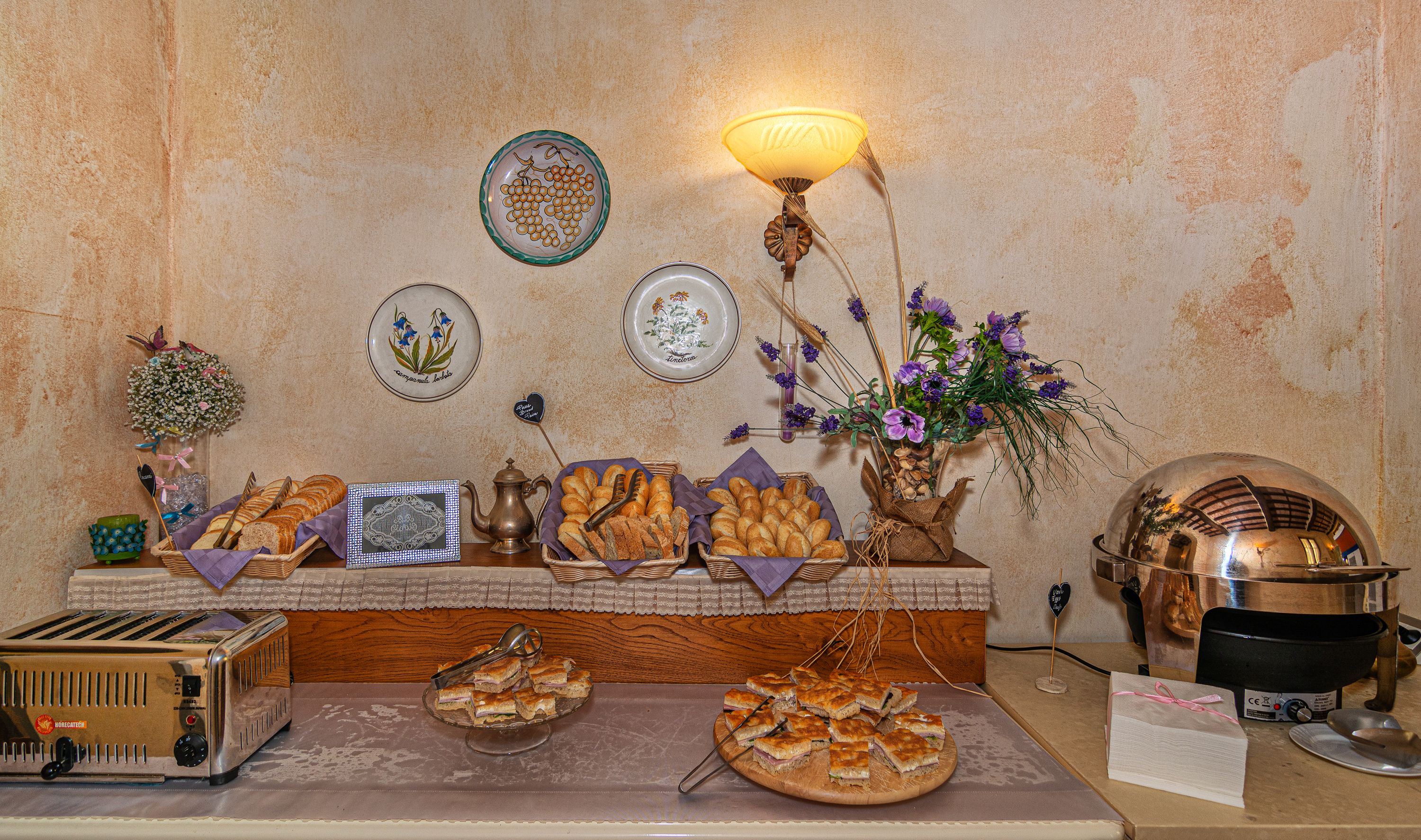 Buffet de café da manhã com pães, bolos e sanduíches.