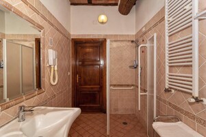 Casa de banho com lavatório, espelho, chuveiro e porta-toalhas.