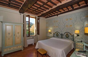 Quarto com cama, duas mesas de cabeceira com luminárias, guarda-roupa e janela com cortinas.