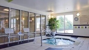 Área de spa com hidromassagem, espaço para sentar e grandes janelas.