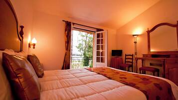 Quarto com cama, escrivaninha, cadeira, televisão e varanda com vista.