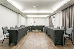 Uma sala de conferências com uma mesa comprida, cadeiras e um extintor na parede.
