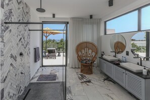 Casa de banho moderna com uma grande janela, zona de chuveiro e toucador com espelho.