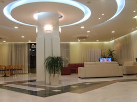 Um lobby moderno com uma coluna central, área de estar e uma tela de televisão.