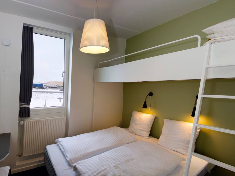 Quarto com beliche, janela, radiador e escrivaninha com cadeira.