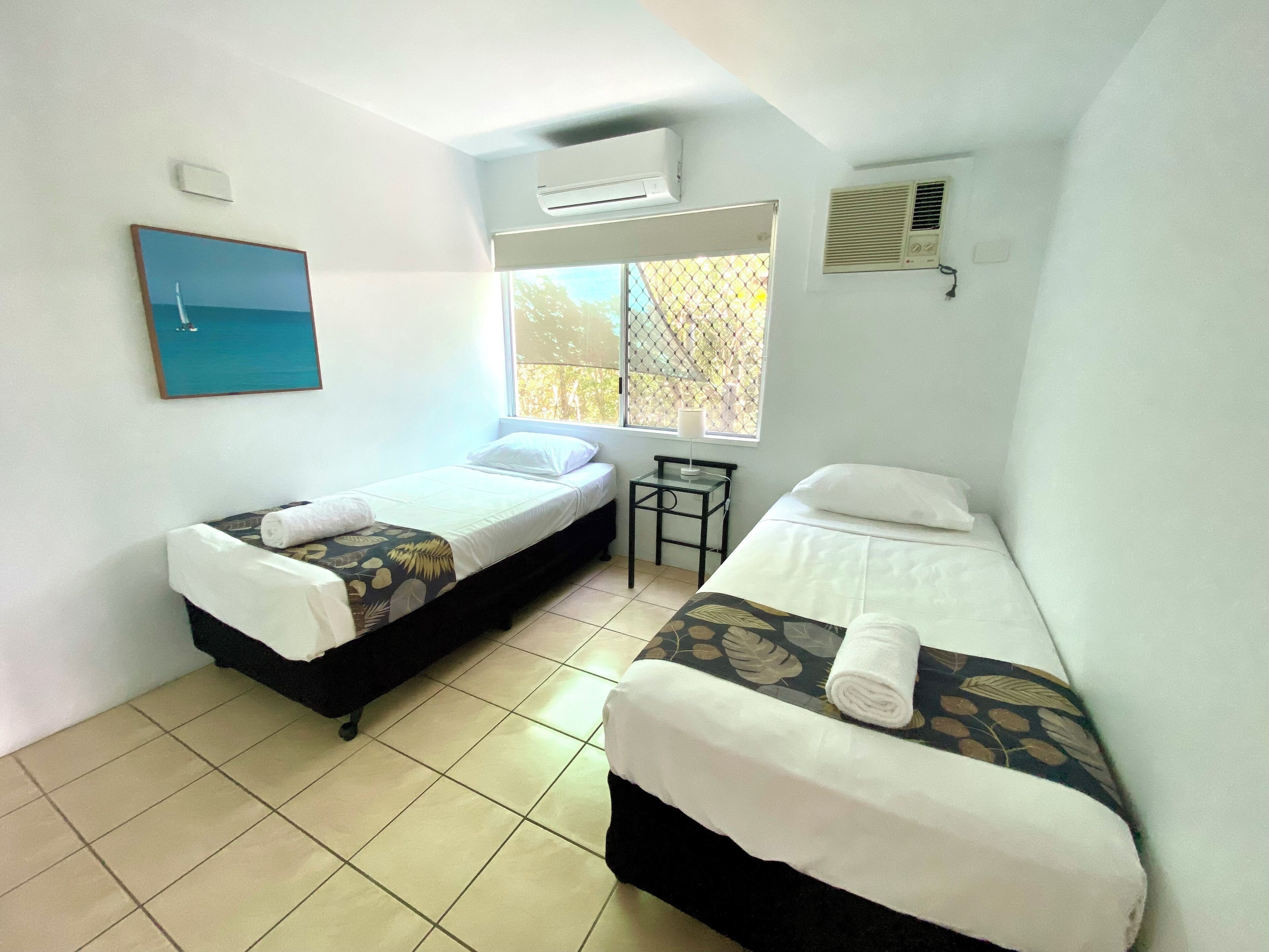 Quarto pequeno e limpo com duas camas, janela com vista e ar condicionado.