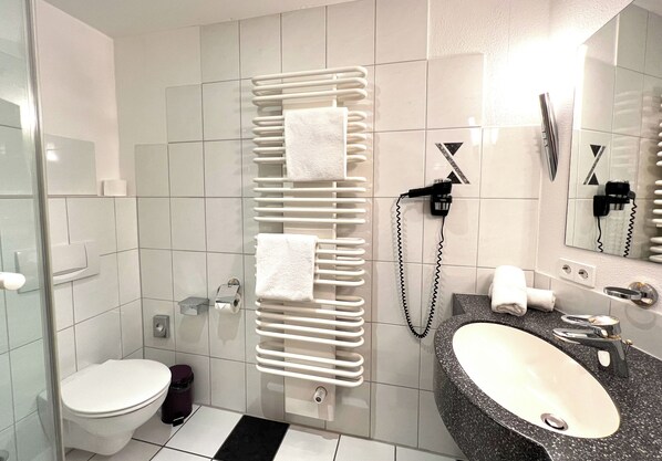 Uma casa de banho moderna com sanita, lavatório e porta-toalhas.