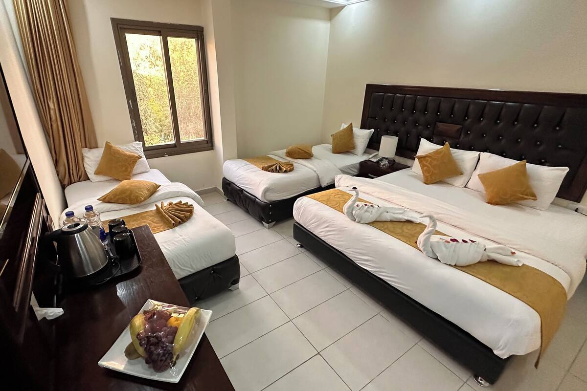 Quarto de hotel com duas camas, uma janela grande, televisão e bandeja de café da manhã.