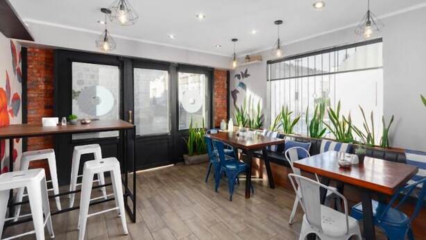Uma sala de jantar moderna com mesa de madeira, cadeiras azuis e brancas e luminárias pendentes.