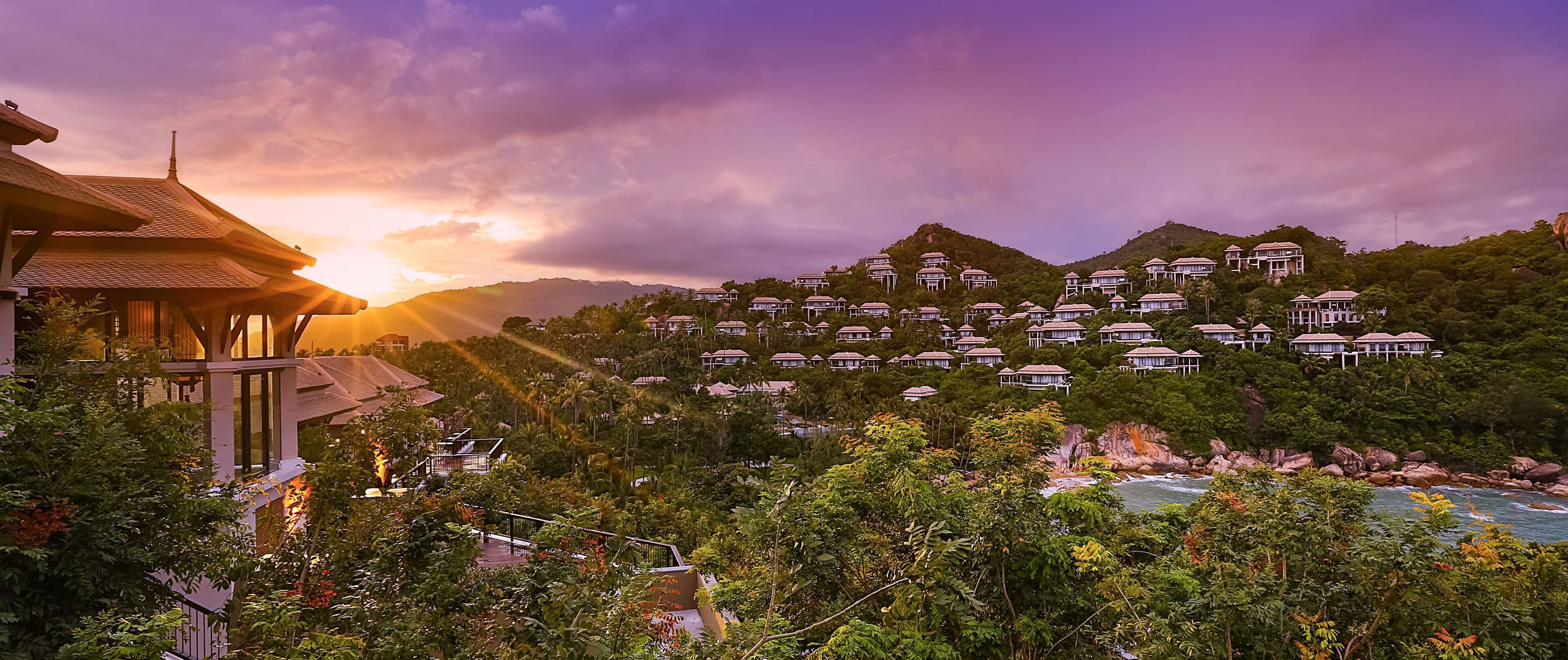 Um resort costeiro com diversas acomodações em estilo bangalô, uma pagoda imponente e uma paisagem verdejante e exuberante.