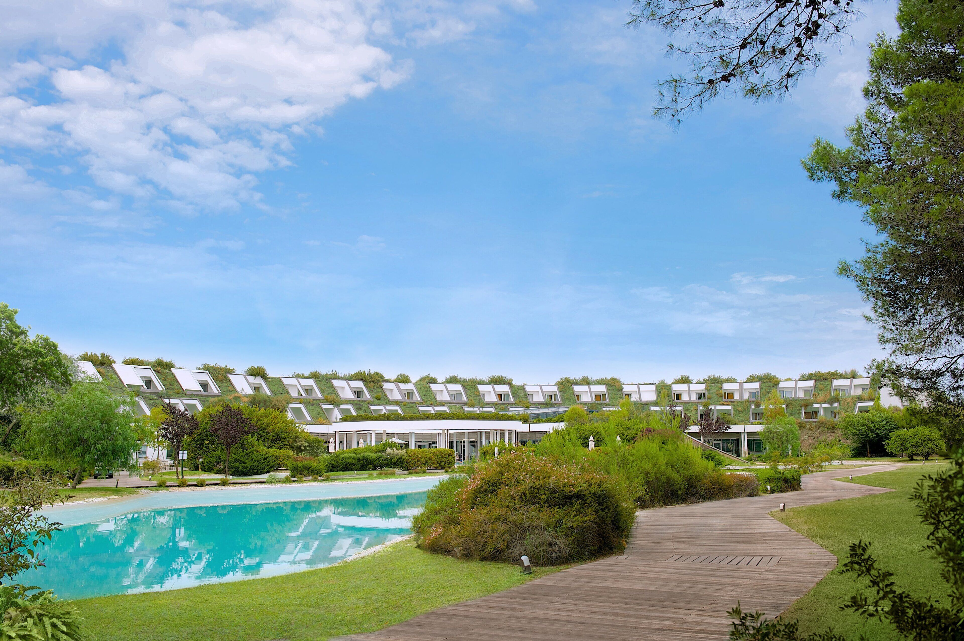 Um resort com piscina, passarelas de madeira e edifícios com telhados verdes.