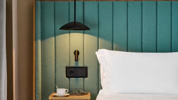 Cama bem arrumada com travesseiro branco e cabeceira azul-turquesa.