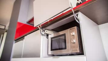 Forno de micro-ondas compacto com visor digital e botões de comando, fixado em superfície metálica com detalhes em vermelho.