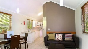 Espaço compacto com área de refeições, kitchenette e sofá.