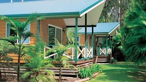 Uma casa de dois andares com telhado verde e varanda coberta.