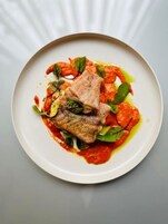 Um prato com carne, vegetais e molho vermelho.
