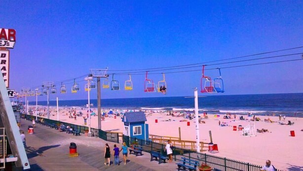 Uma praia com calçadão, cadeiras de praia e uma torre de salva-vidas.