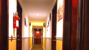 Corredor de hotel com portas de madeira, um extintor de incêndio e um sinal de saída.